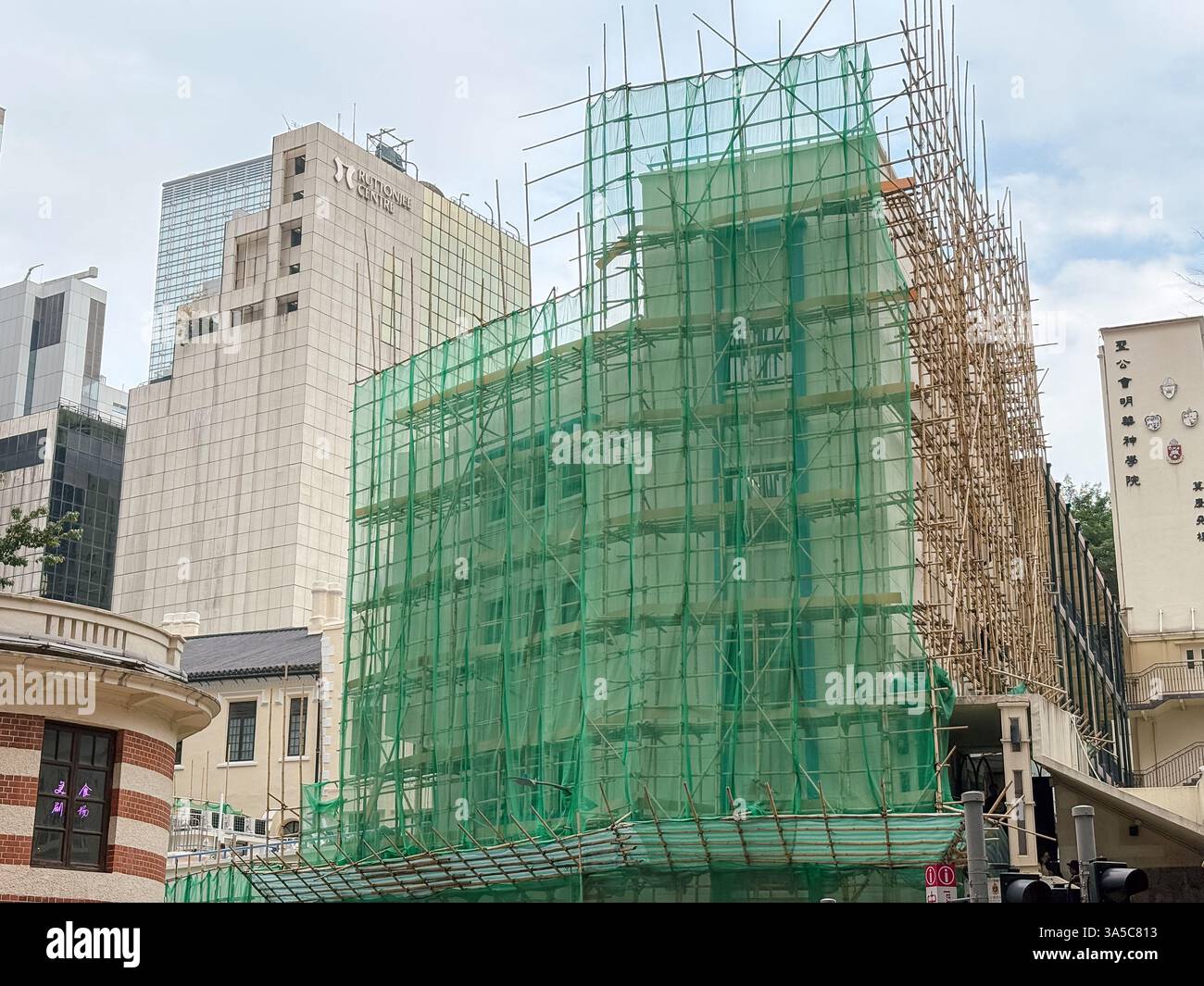 A building under construction in Hong Kong, covered in green netting and bamboo scaffolding ...