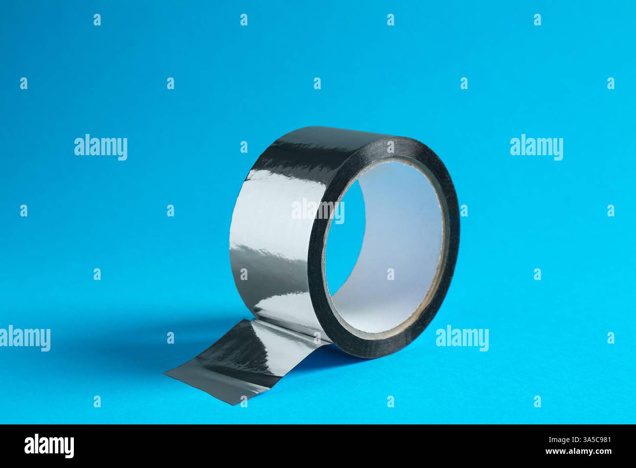 Roll of silver adhesive tape on light blue background Stock Photo - Alamy