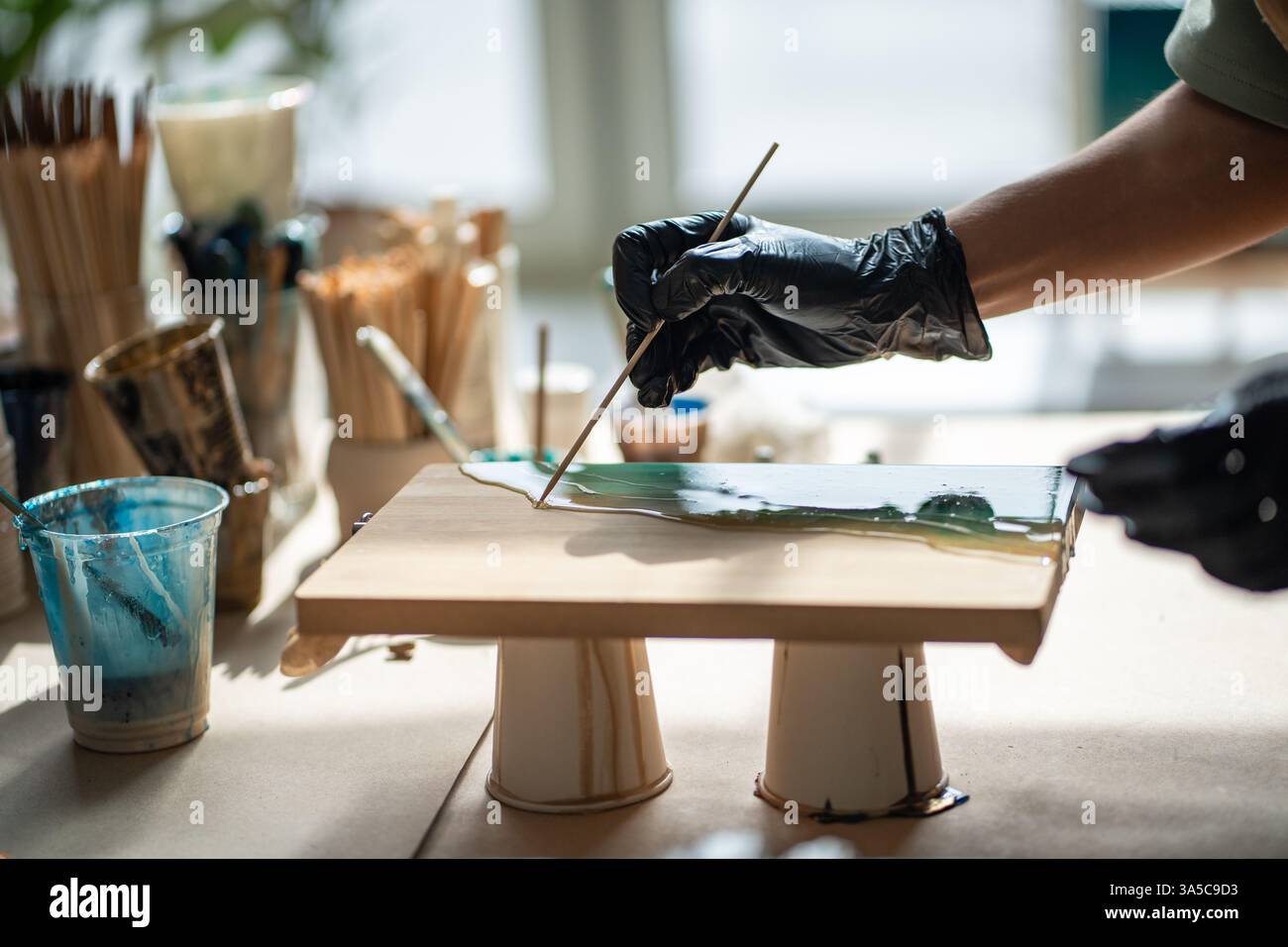 Craftswoman use wooden stick to form river wave pattern on wooden panel ...