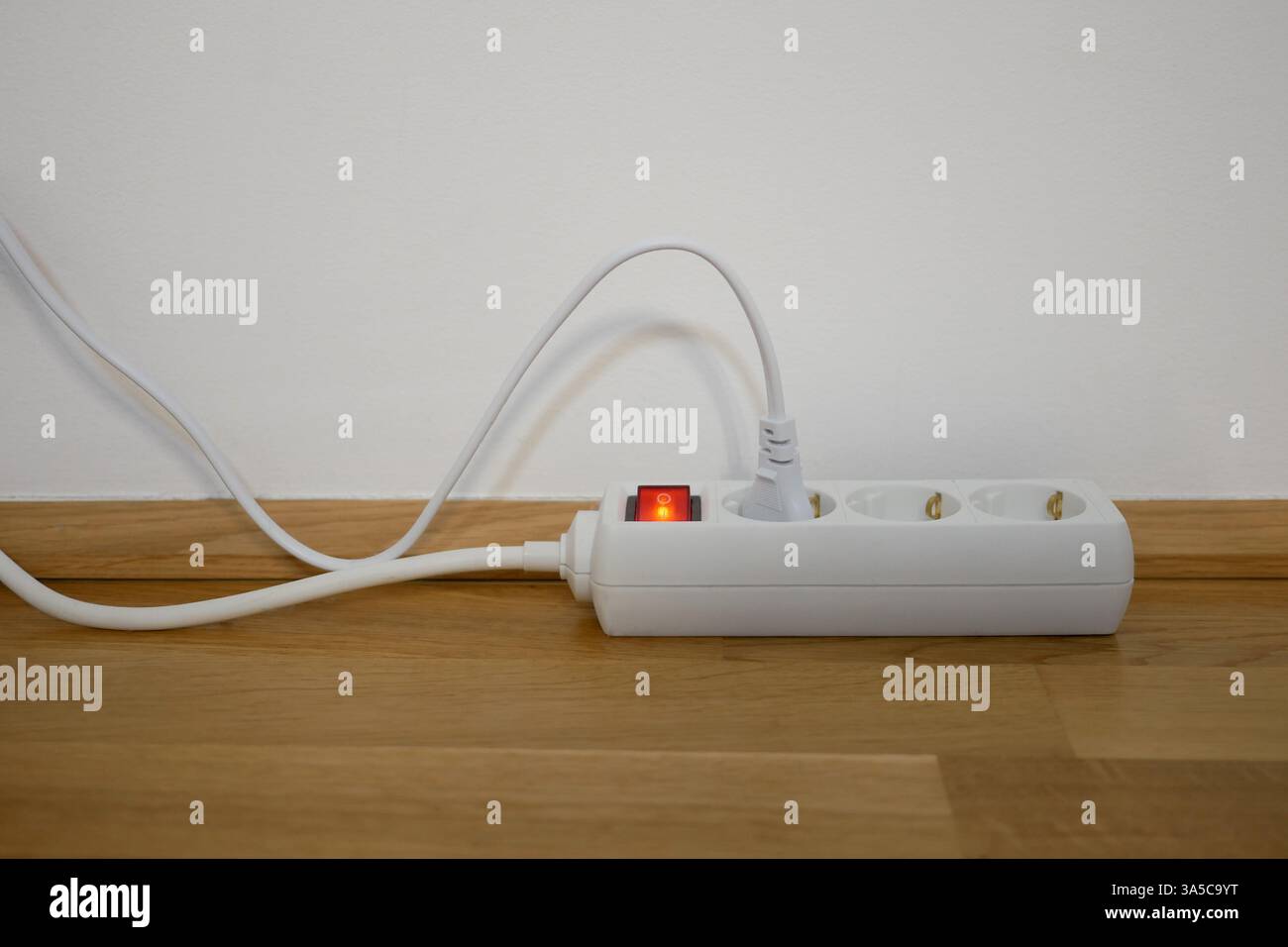 The electric cable is plugged into a power strip socket extension cord ...