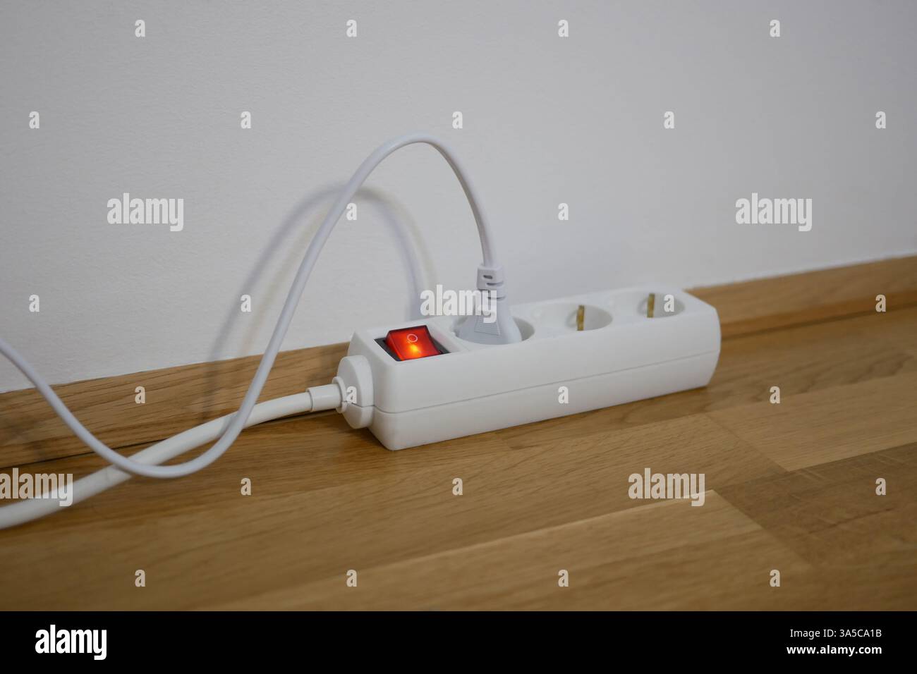 The electric cable is plugged into a power strip socket extension cord ...