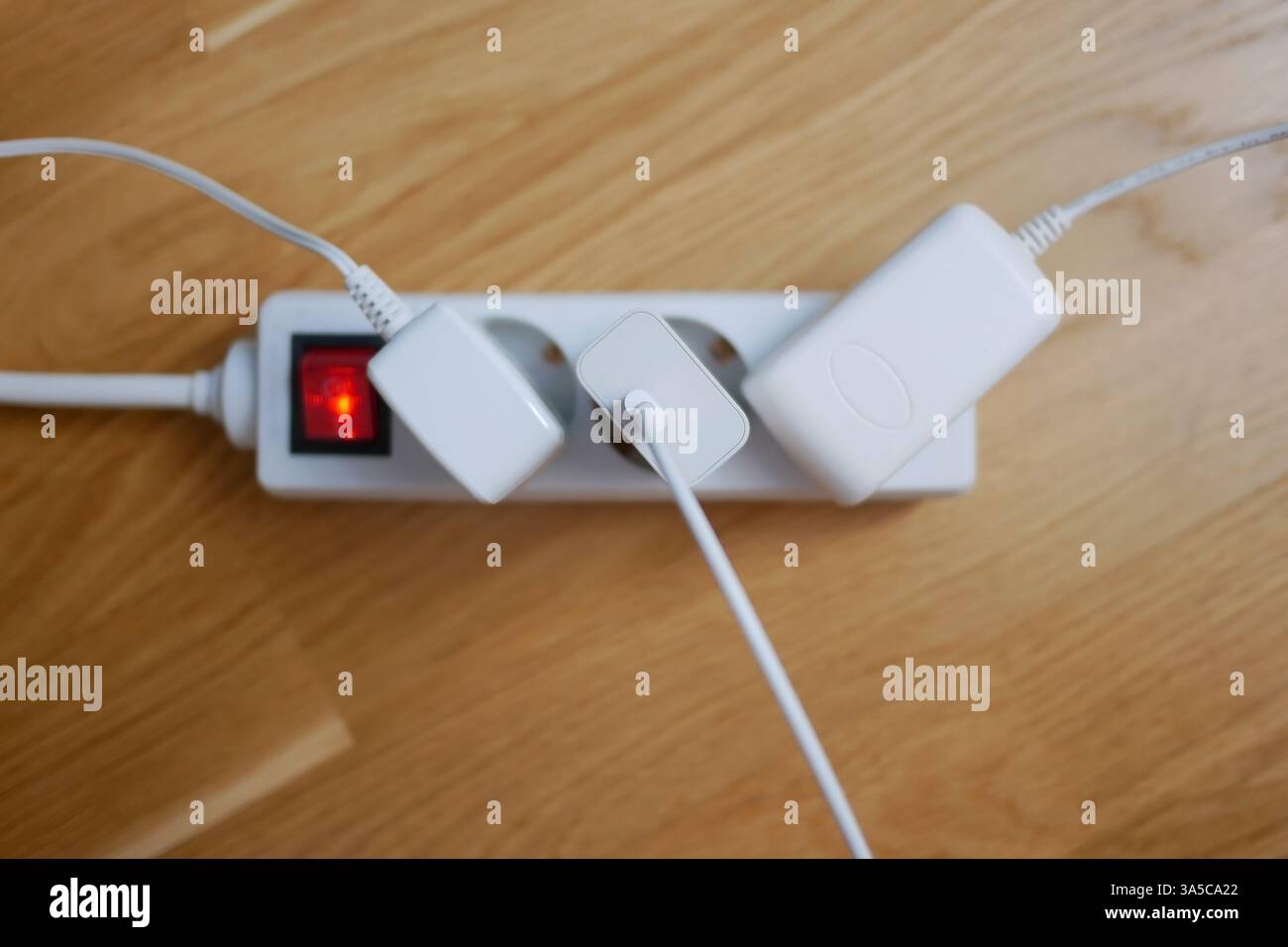 Three electric cables are plugged into a power strip socket extension ...