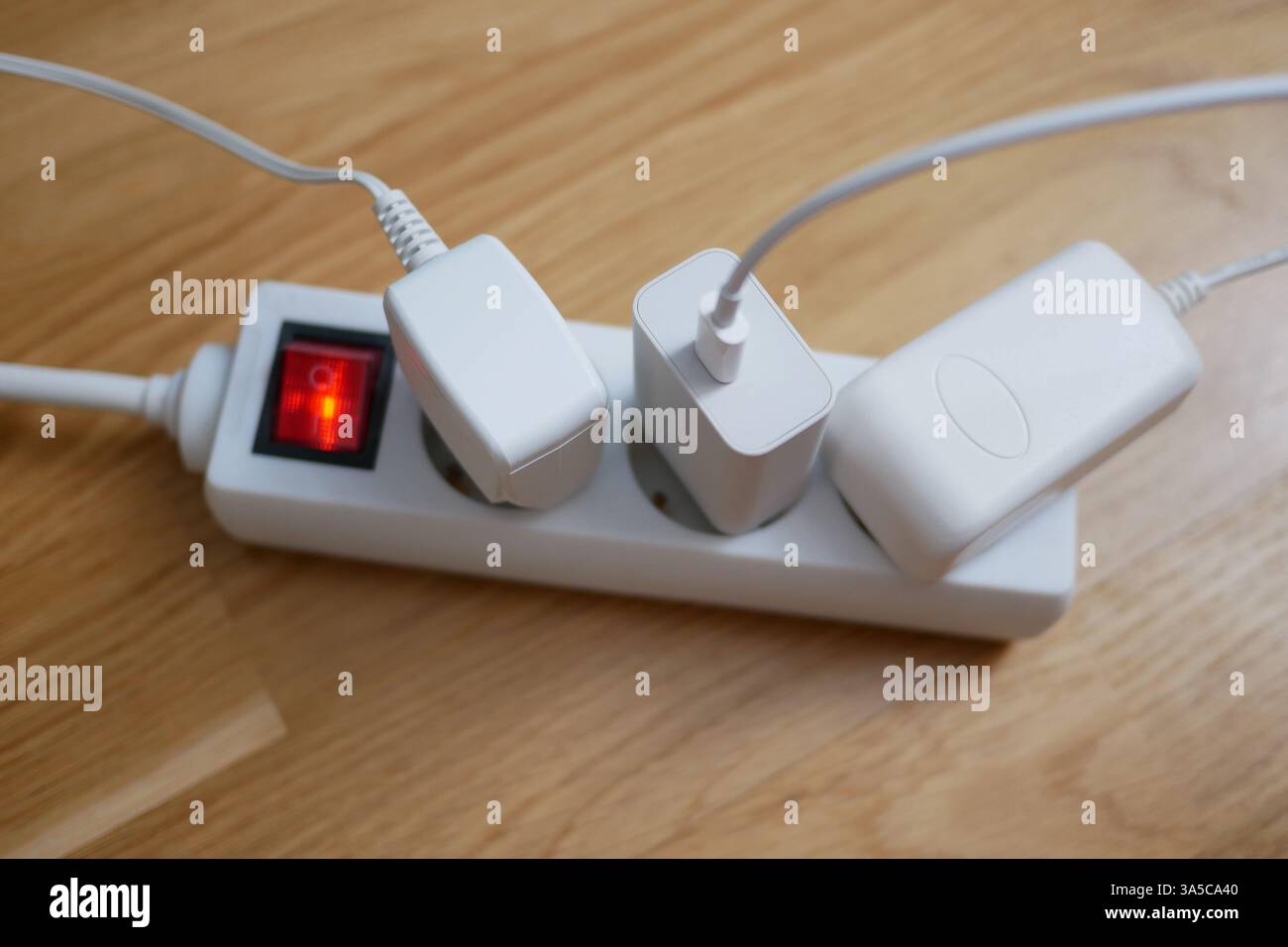 Three electric cables are plugged into a power strip socket extension ...