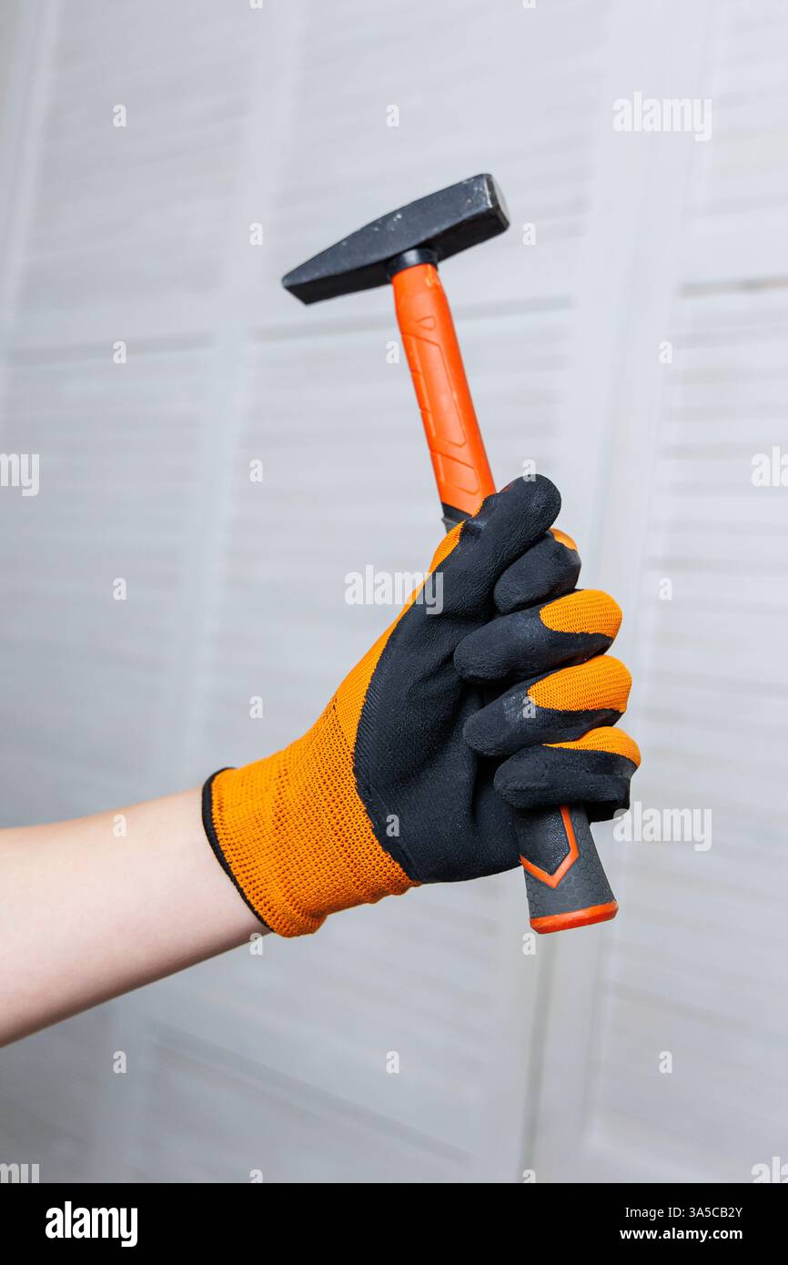 A closeup image captures a workers hand firmly gripping a hammer ...