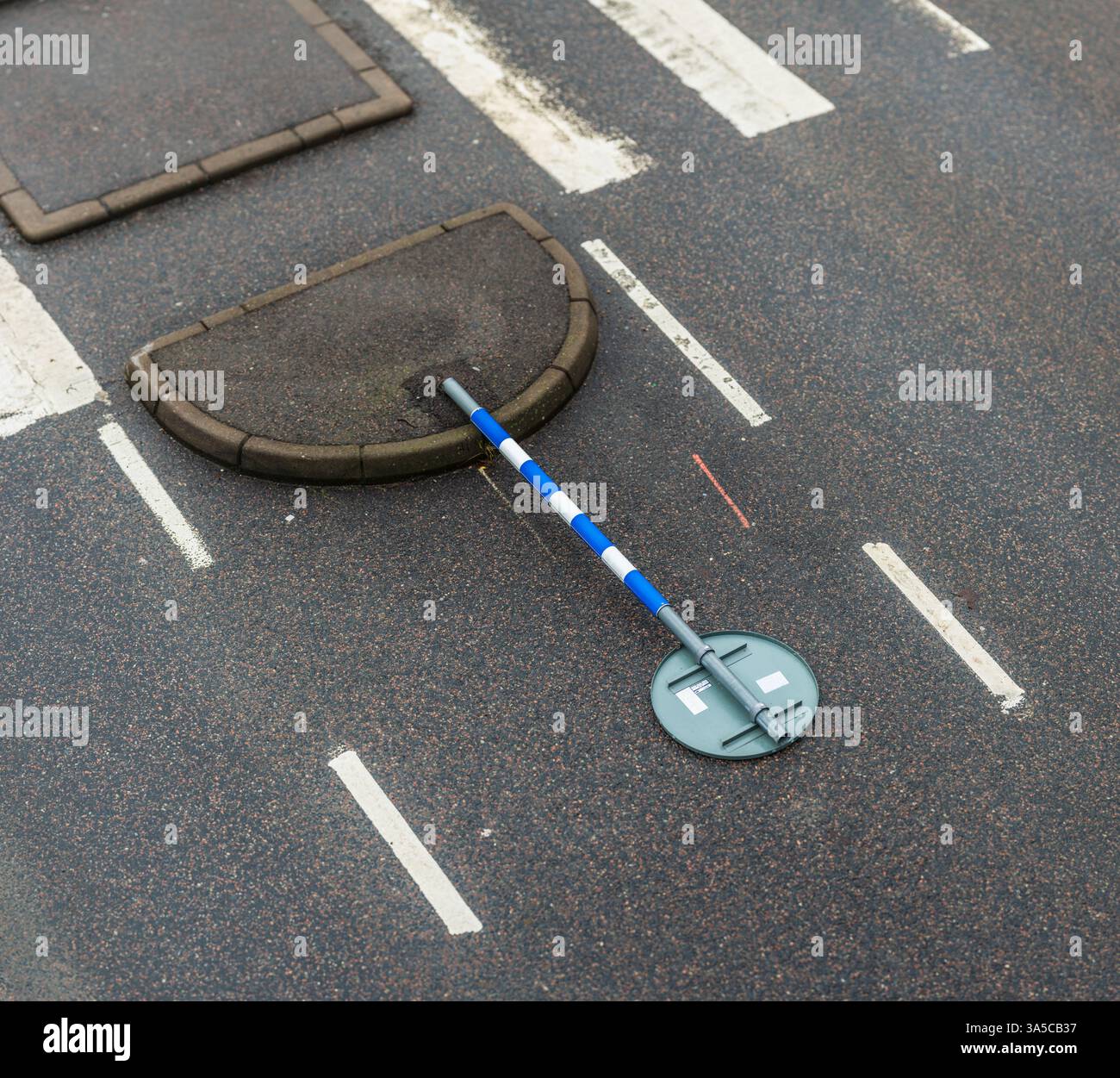 road with white lane markings and fallen blue and white striped pole ...