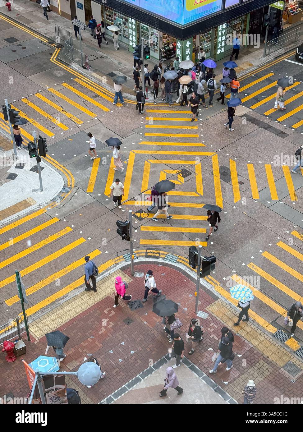 High-angle view of pedestrians crossing a street in Tsim Sha Tsui, Kowloon, Hong Kong, with ...
