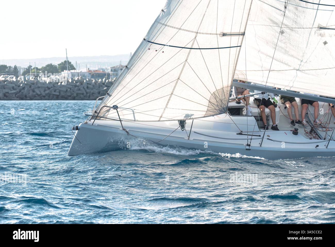 Sailors navigating a sailboat during a regatta, with the sail taut and ...