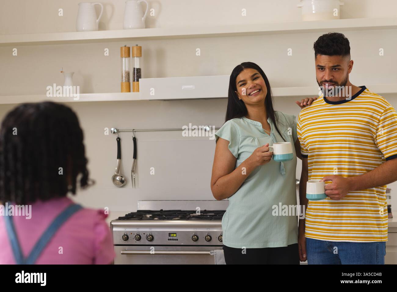 Parents enjoying coffee in kitchen while smiling at their child Stock ...
