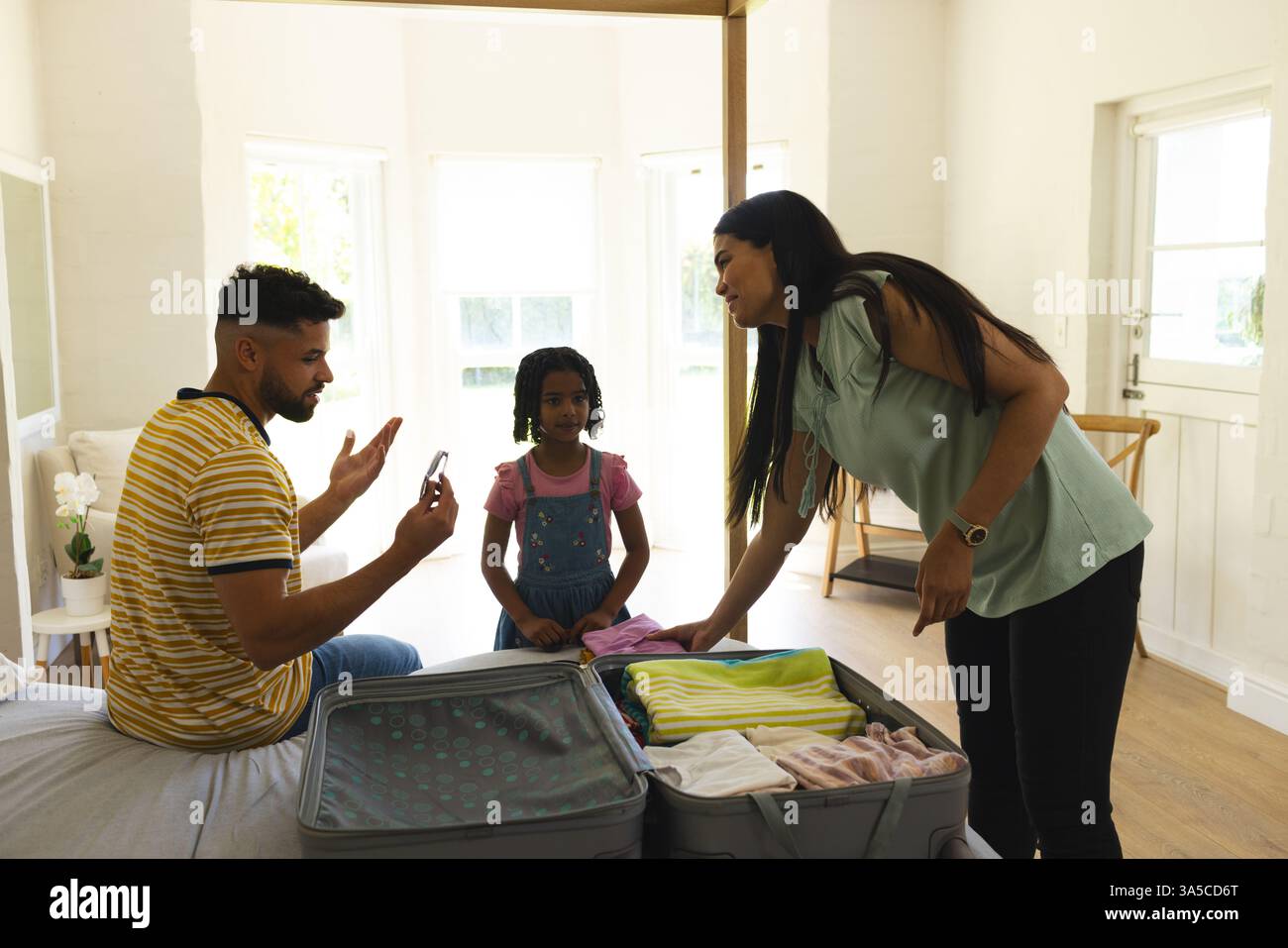 Packing for vacation, parents and daughter organizing clothes in ...