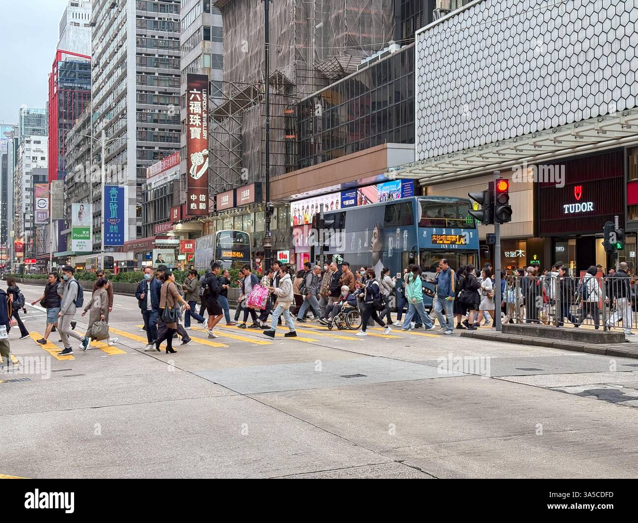 People crossing at a busy crosswalk on Nathan Road in Hong Kong, with ...