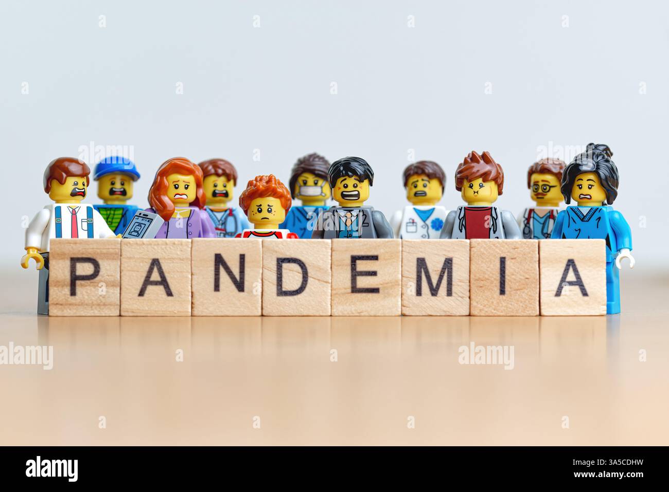 Group of worried lego people are standing behind scrabble tiles ...