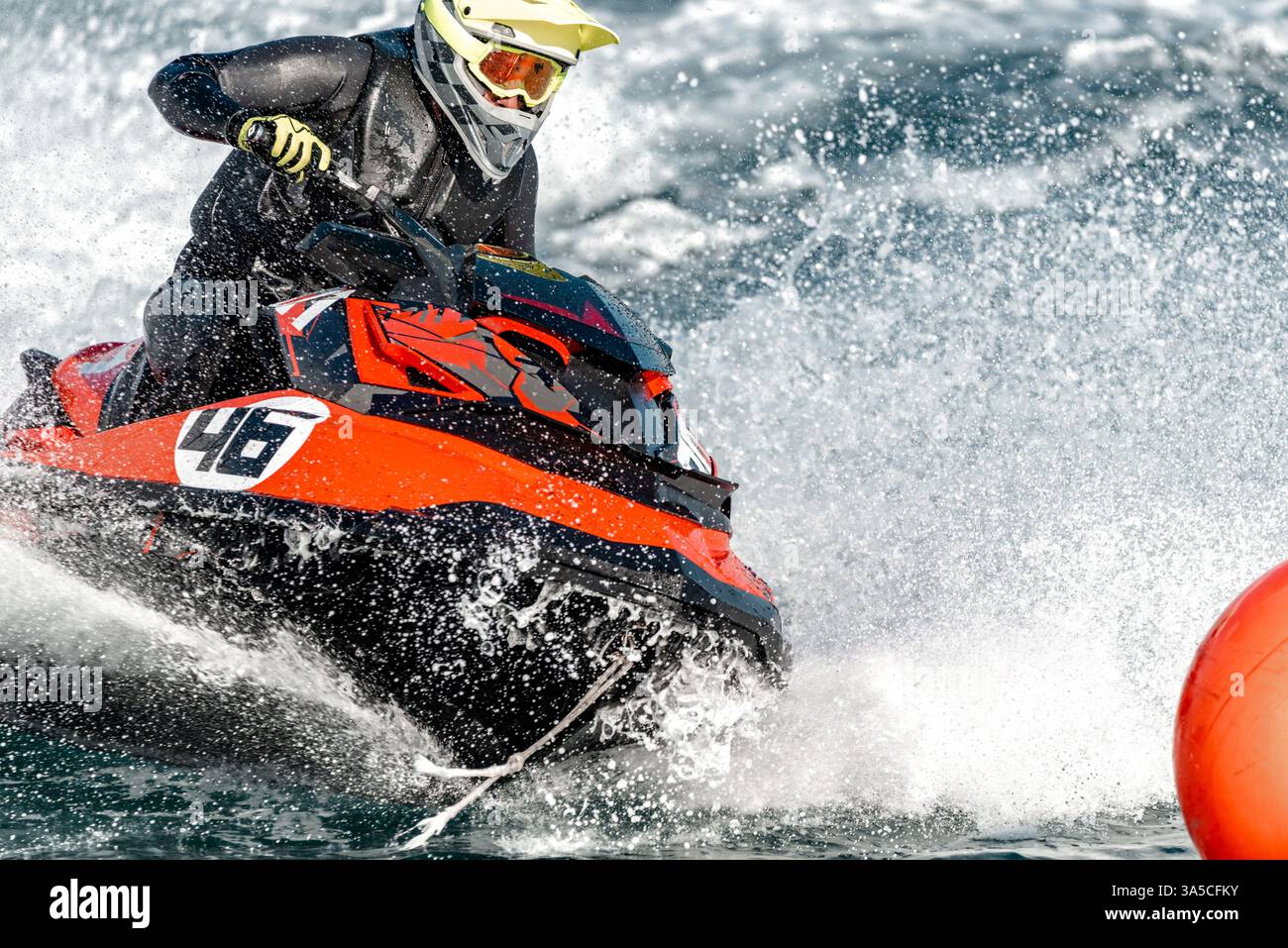 Pilot riding a jet ski at high speed on the waves during a competition ...