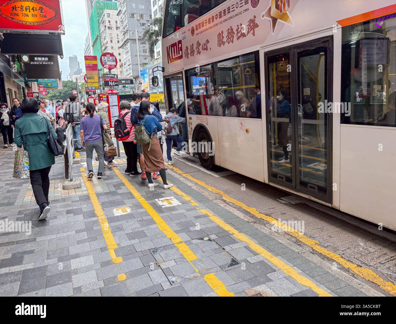 A KMB bus picking up passengers at a bus stop in Kowloon, Hong Kong ...