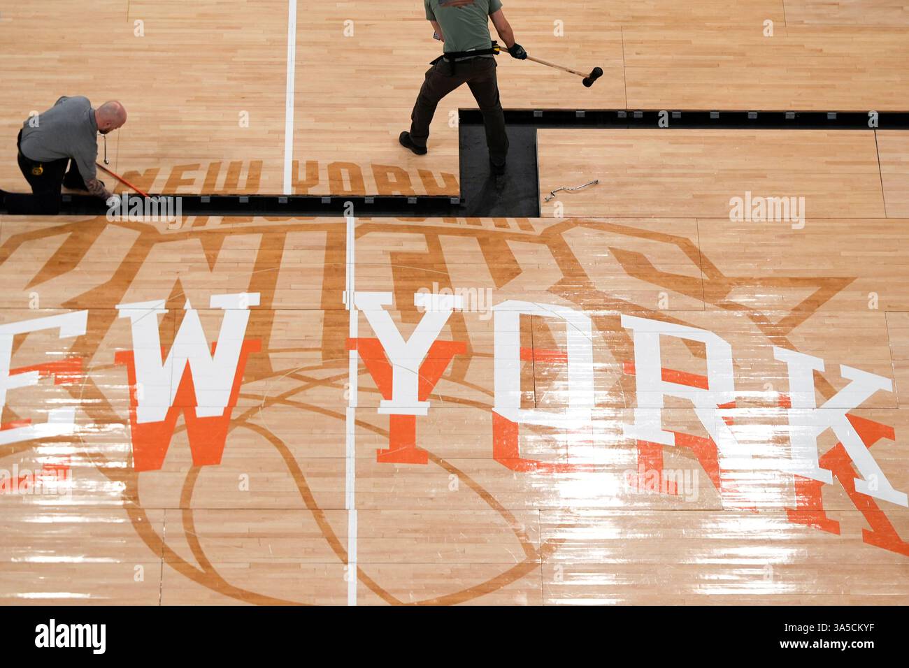 Workers install the basketball court over the ice at Madison Square ...