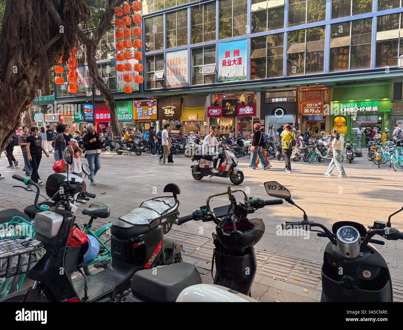 A busy street scene in Guangzhou, China filled with motorbikes and ...