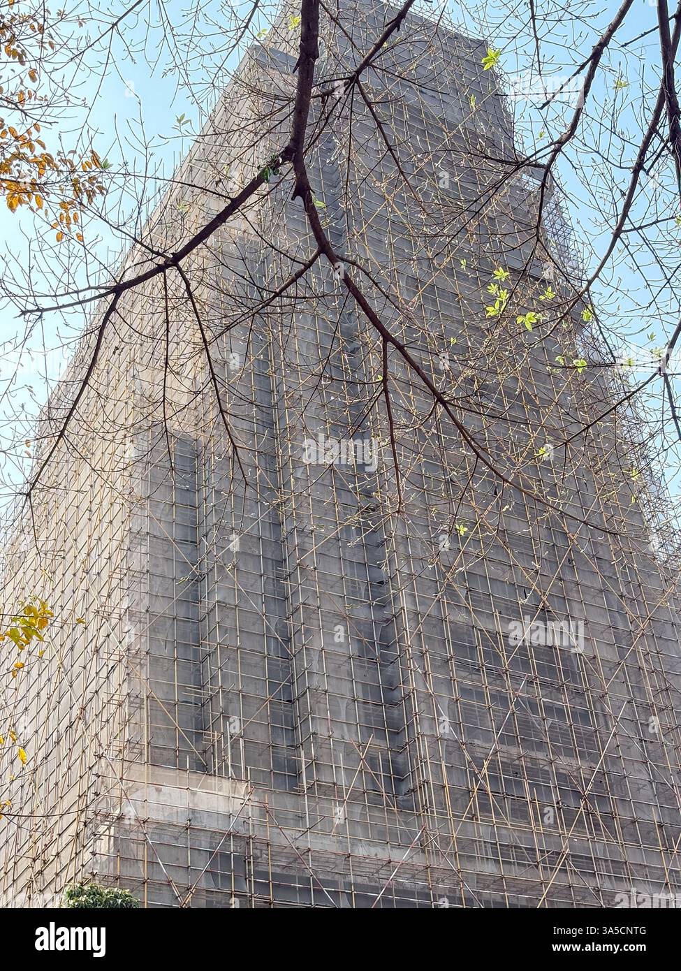 A high-rise building covered in scaffolding in China. Construction and ...