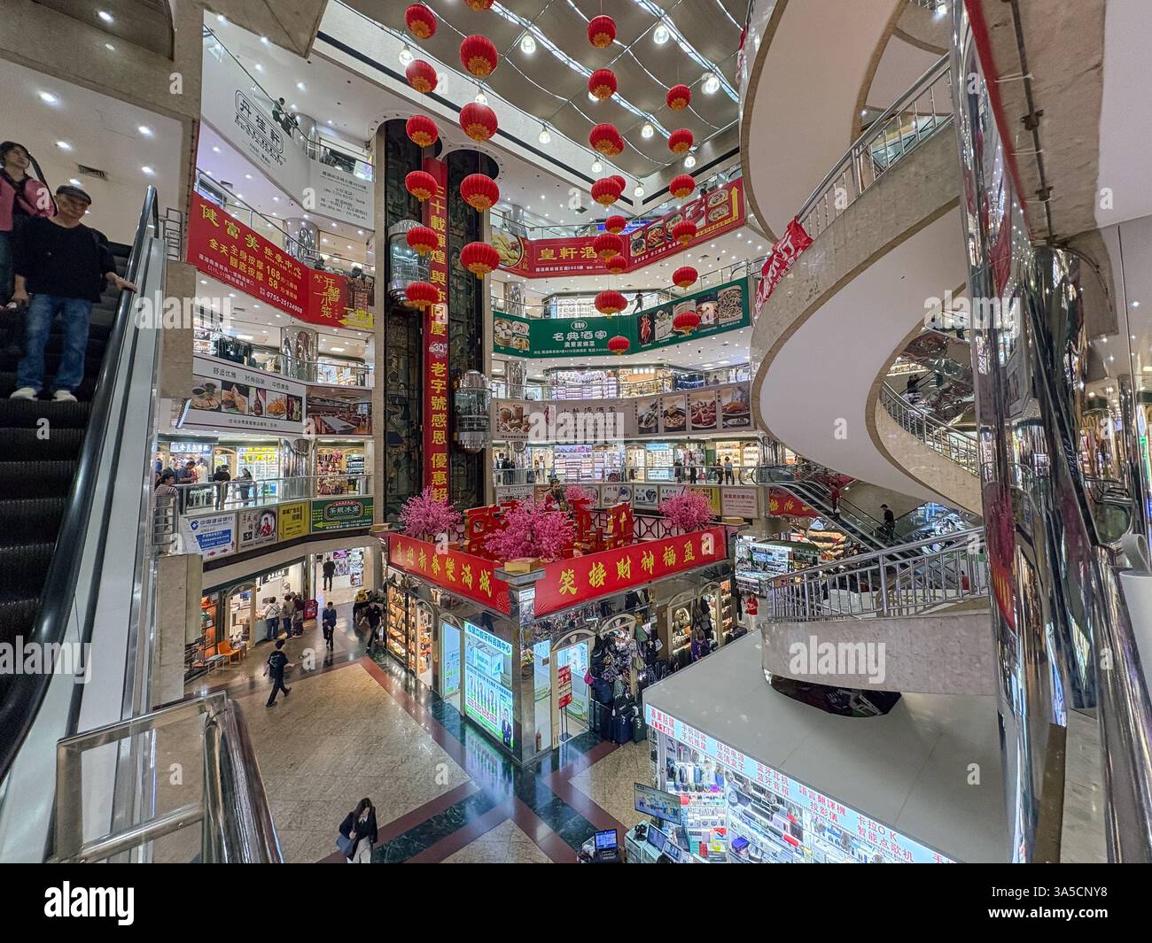 An indoor multi-level shopping mall in China. Retail shops, escalators ...