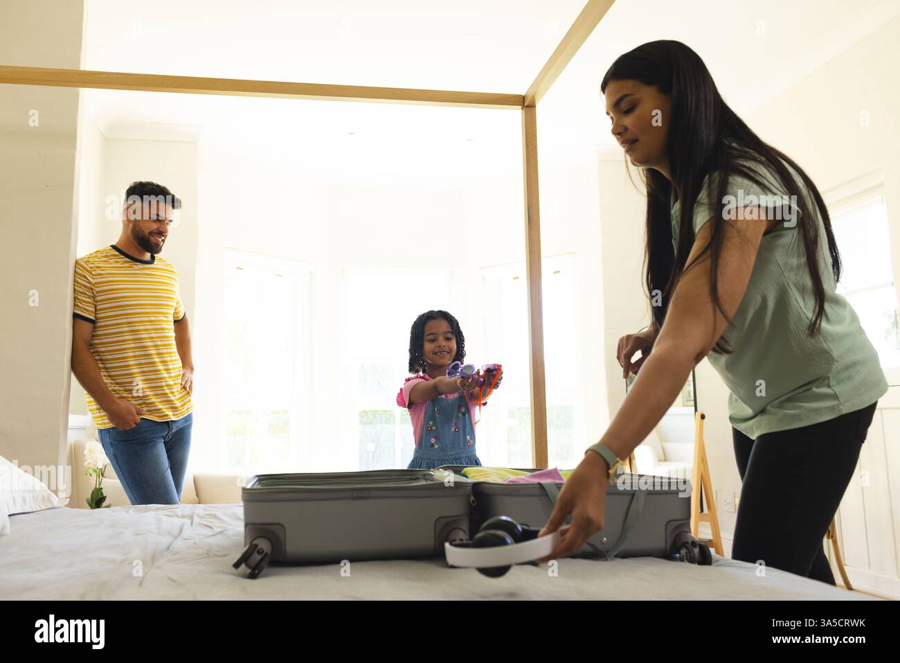 Family packing suitcase at home, preparing for vacation with happy ...