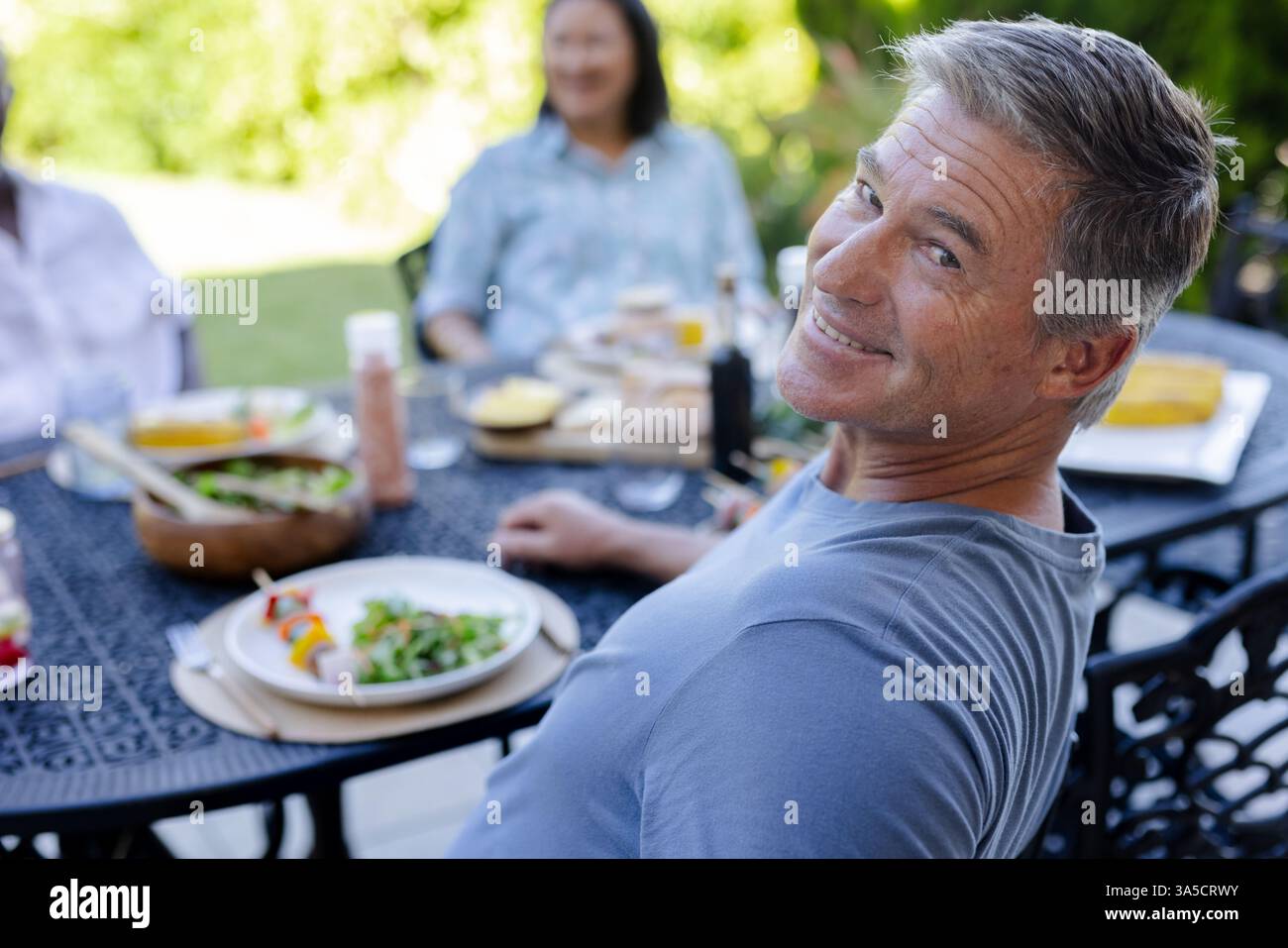 Smiling man enjoying outdoor lunch with Senior friends, relaxing in ...