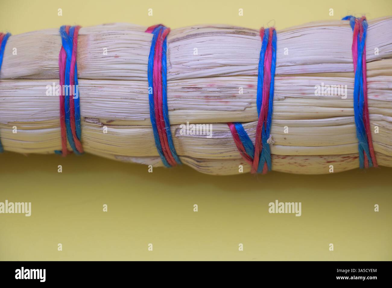 A close-up of the braided straw broom, with several thick and thin ...