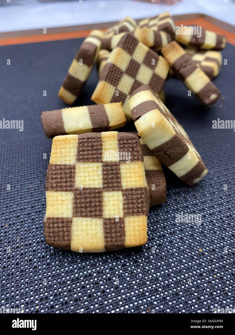 Colorful checkered cookies are artfully stacked on a dark textured ...