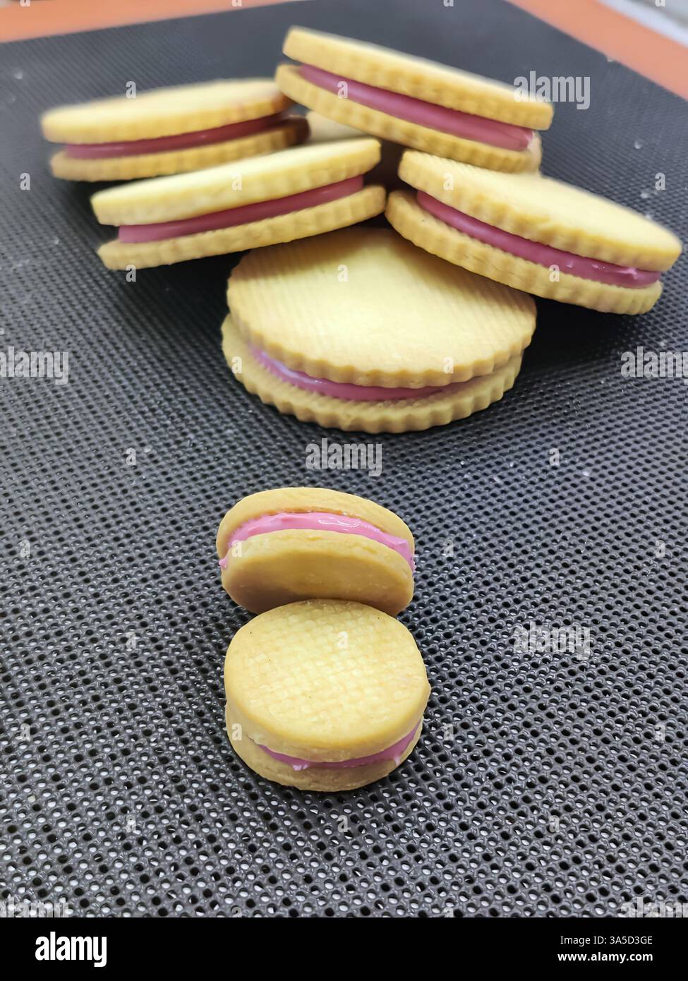 Several beautifully crafted cream-filled cookies are stacked on a ...