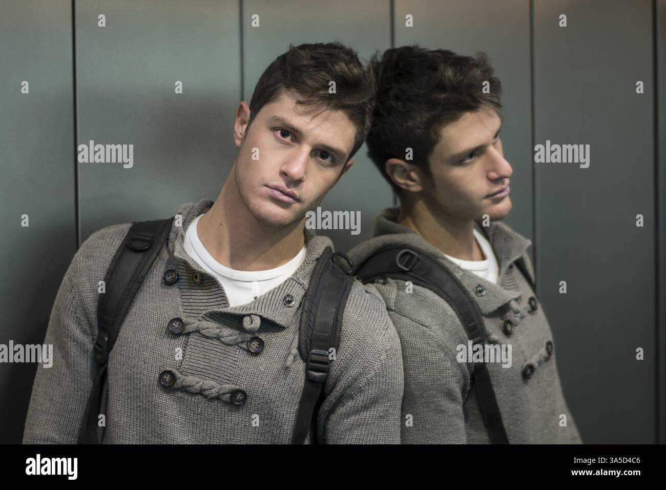 Handsome young man leaning against mirror inside an elevator (lift ...