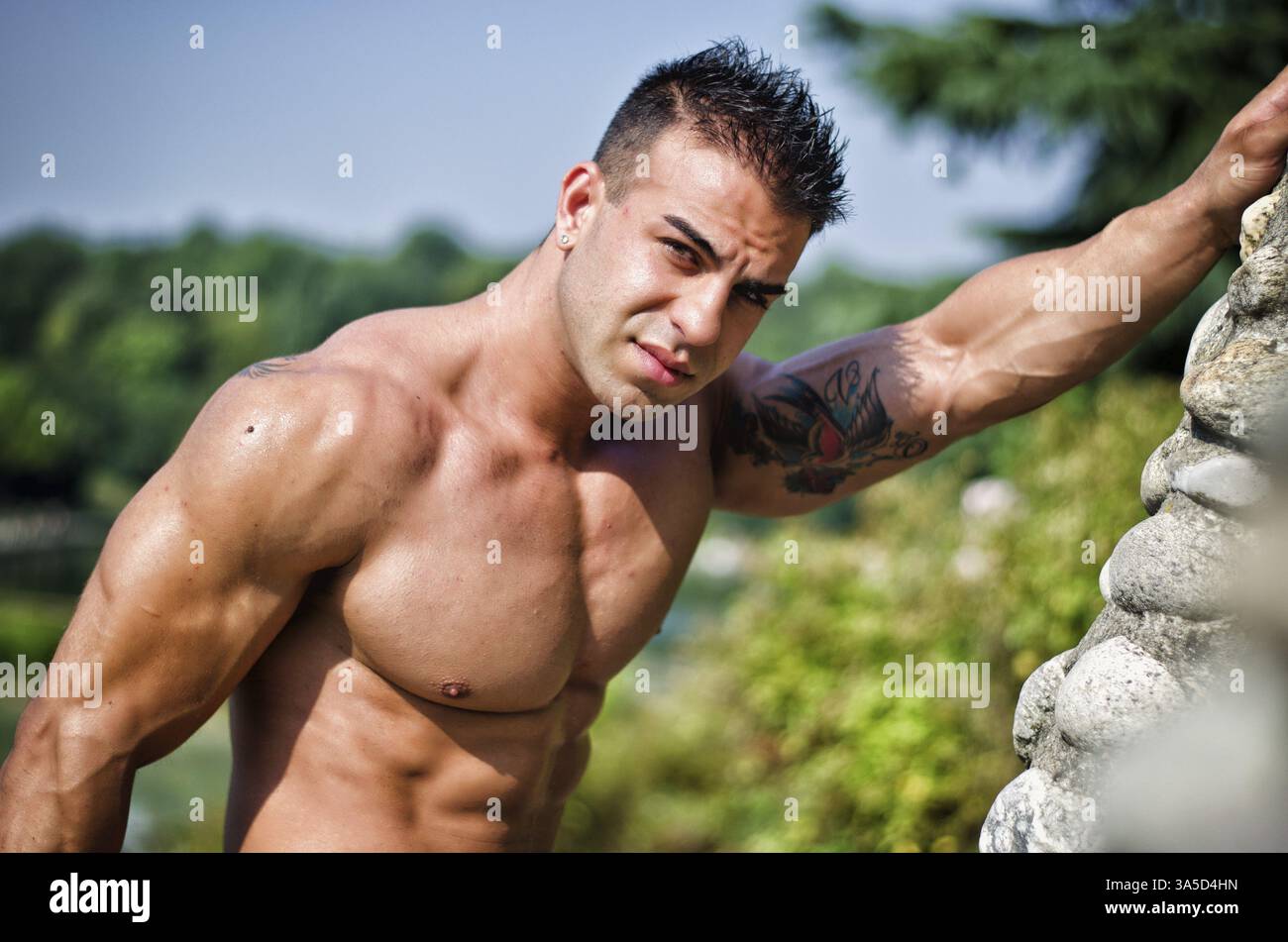 Attractive young bodybuilder outdoors, leaning against stone wall Stock ...
