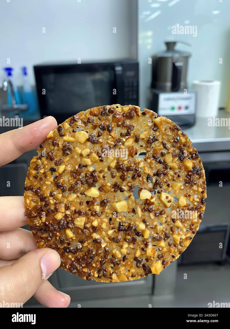 A close-up of a round, thin, nutty cookie with a caramelized appearance ...