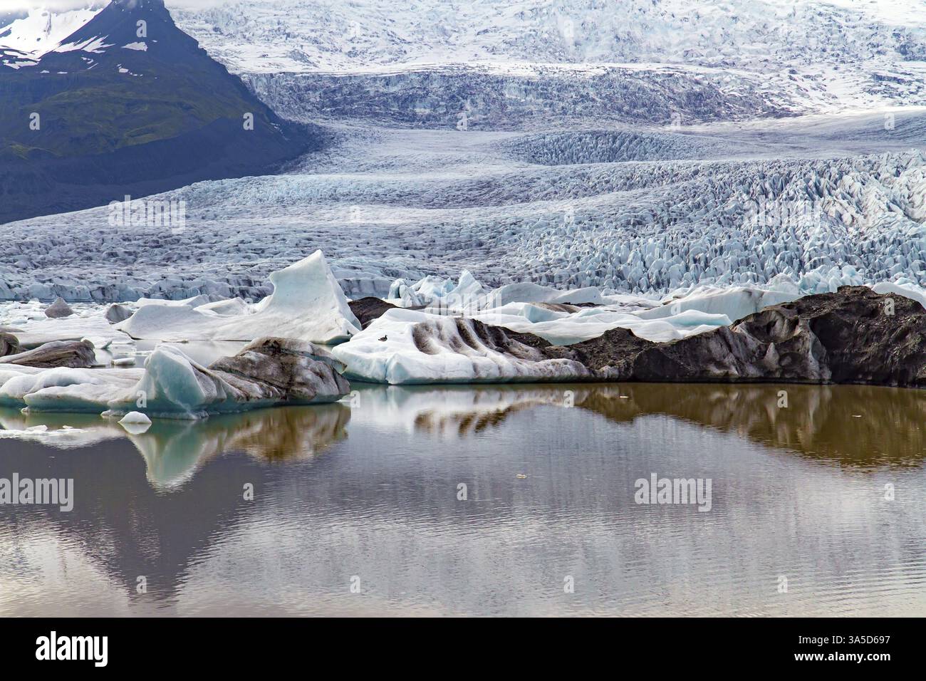 Blocks of ice are reflected in smooth water. Jokulsarlon glacial lagoon ...