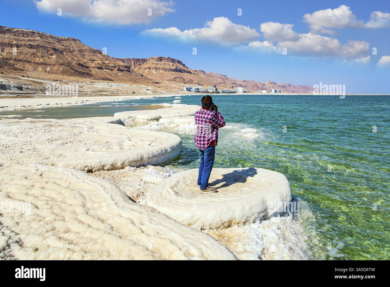 Woman in a plaid cowboy shirt photographs the sea surface. Evaporated ...