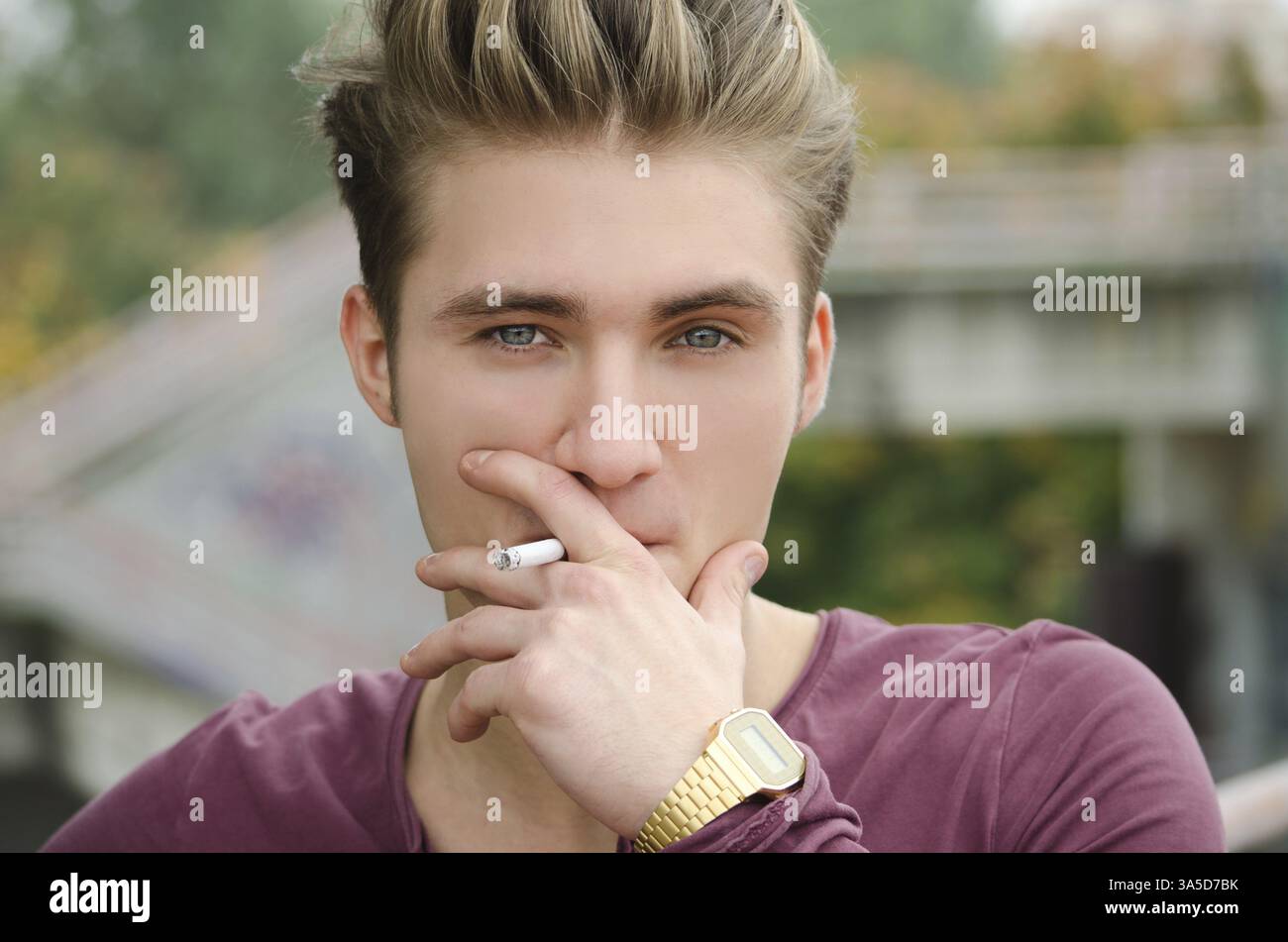 Attractive blue eyed, blond young man smoking cigarette outdoors Stock ...