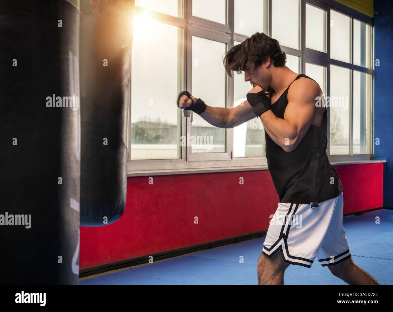 Side view of muscular sportive man in modern gym training with punching ...