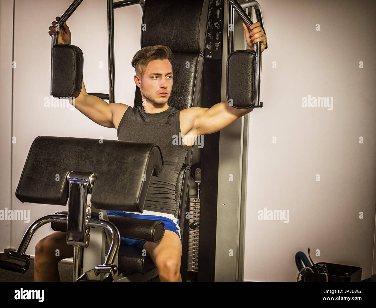 Muscular young man, training pecs on gym cable machine Stock Photo - Alamy