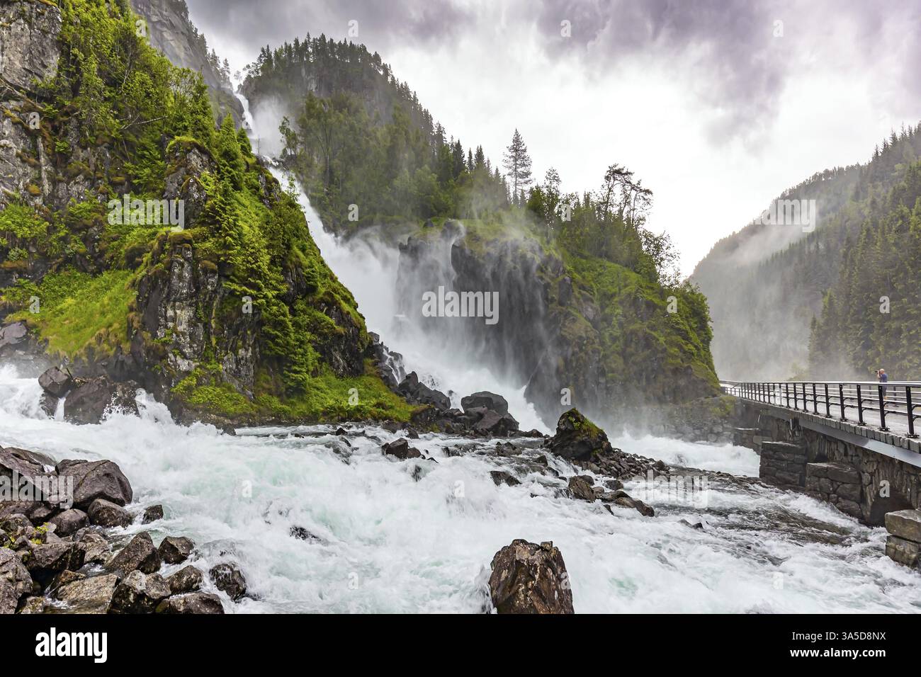 Powerful double waterfall Lotefossen. The road passes through water ...