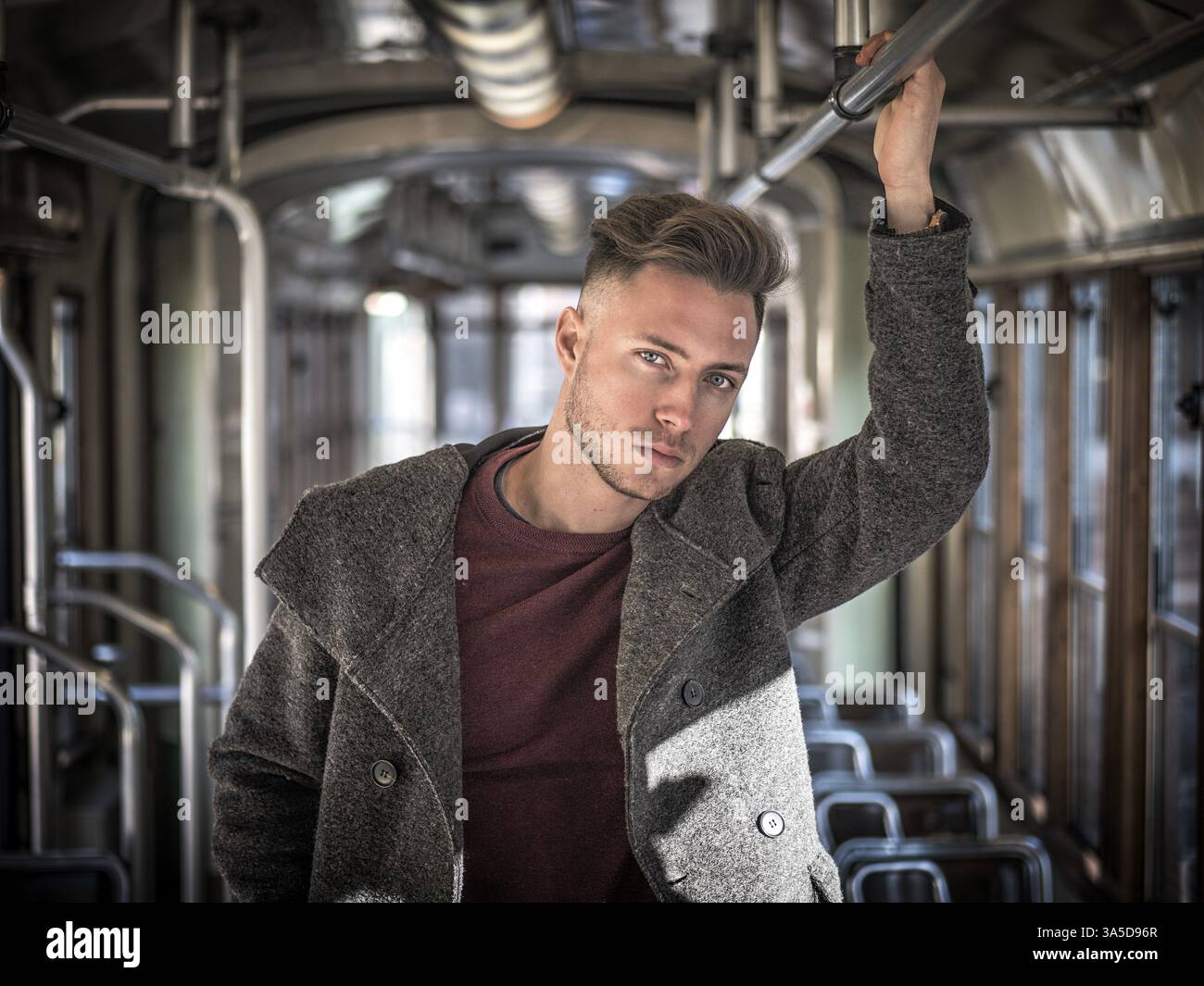 Young handsome man riding on tram or old bus in city, wearing winter ...