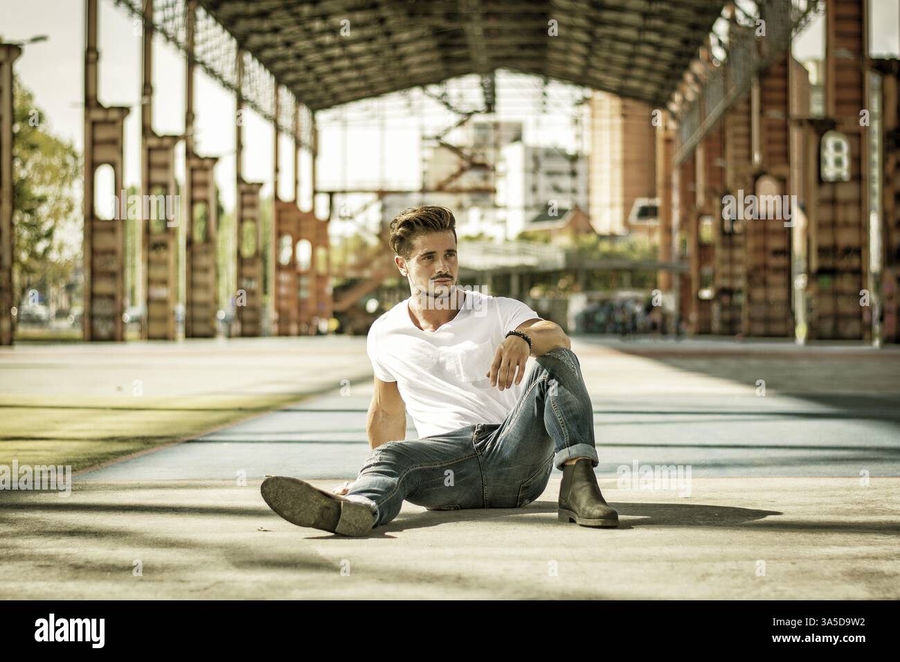 Attractive man in urban setting under big metal structure, a former ...
