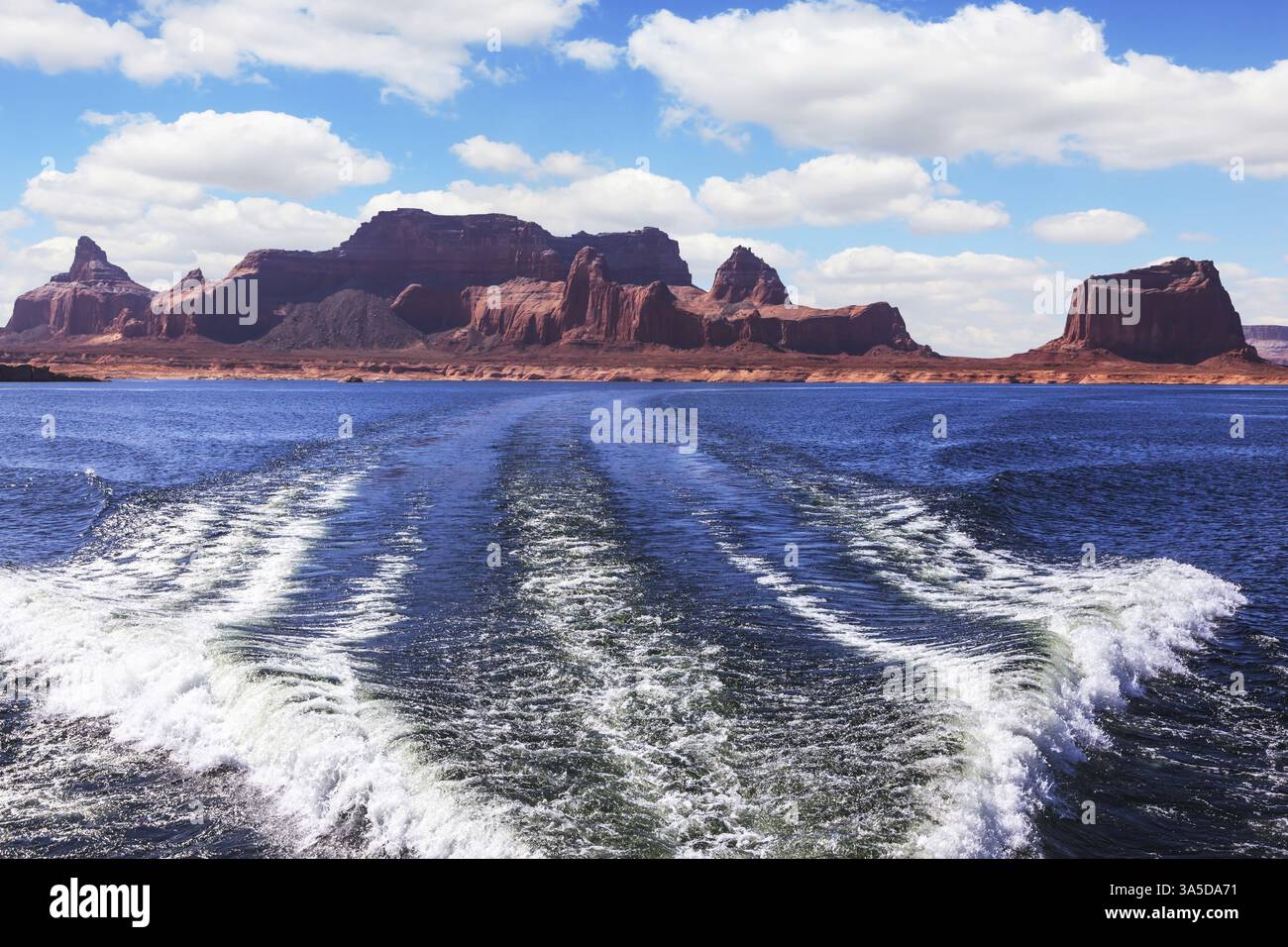 Foamy trace of a motor boat crosses the emerald waters. In distance the ...