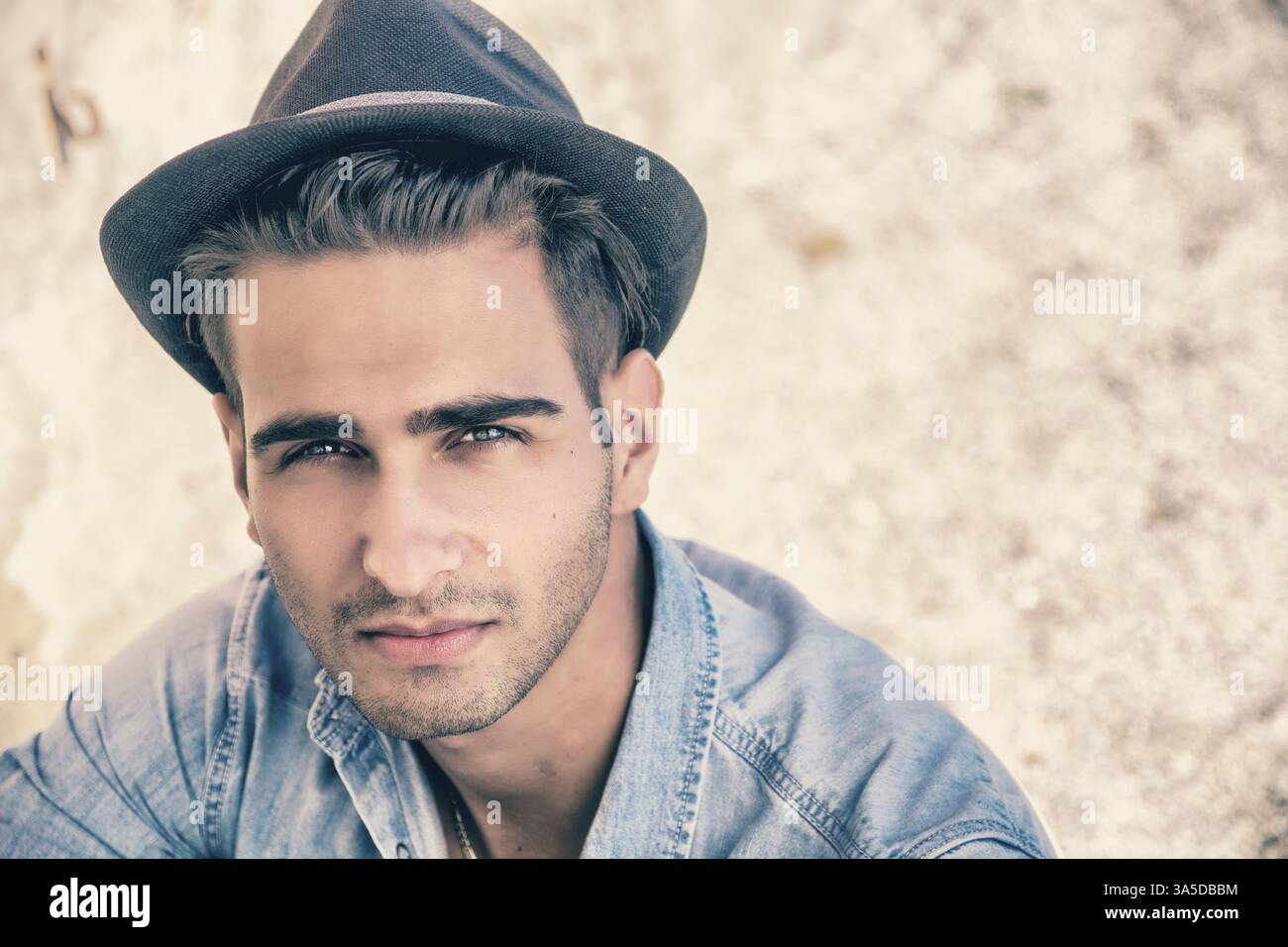 Handsome young, man in denim shirt and fedora hat sitting in pose on ...