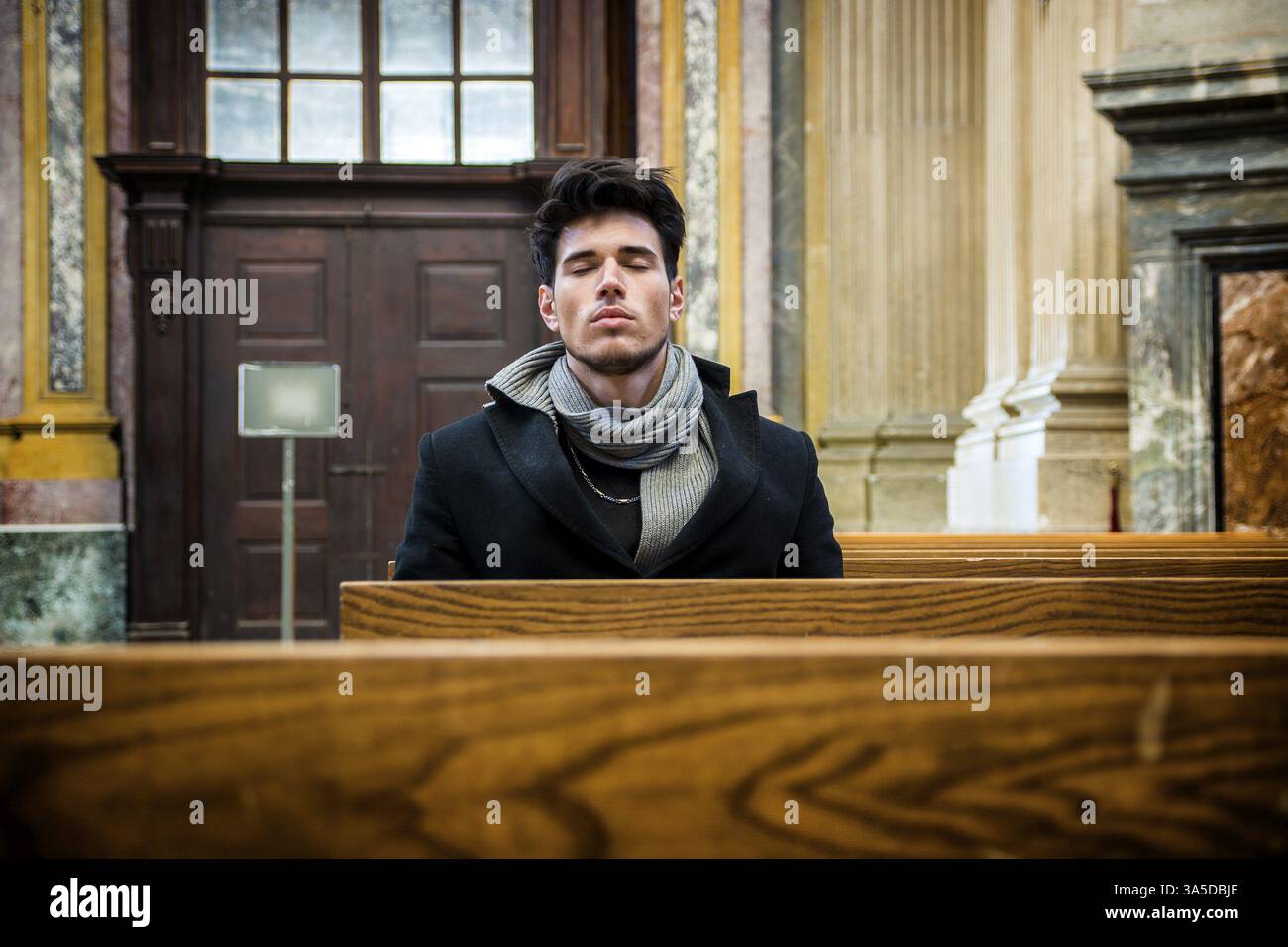 Young man sitting and kneeling in church praying, on wood bench Stock ...