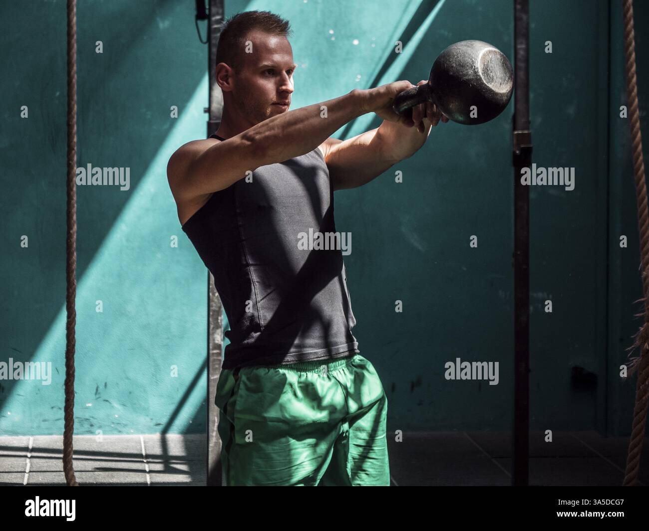 Young man working out with kettlebells in gym, standing Stock Photo - Alamy