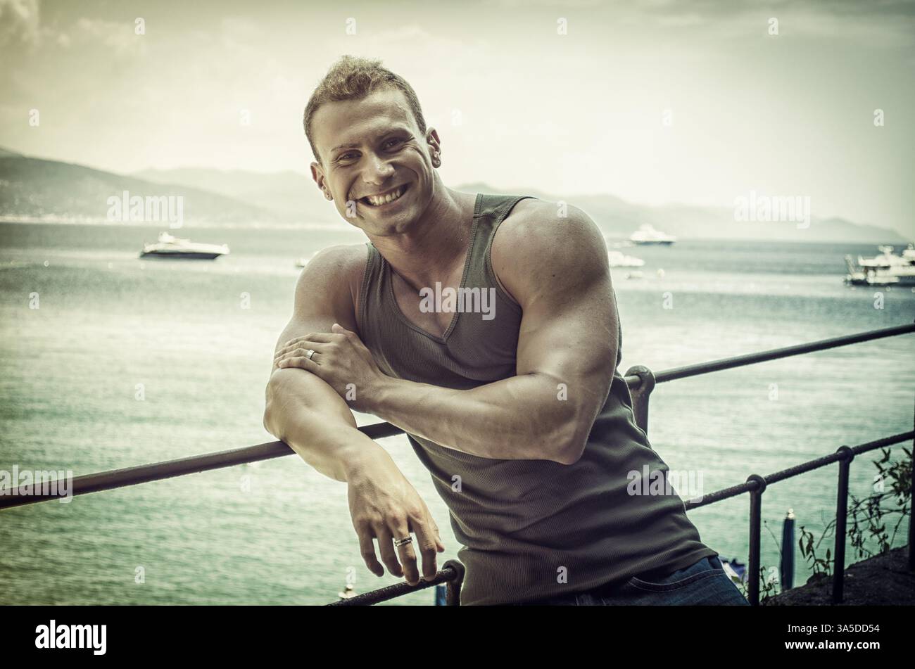 Handsome young muscle man at the seaside, outdoors, in front of the sea ...