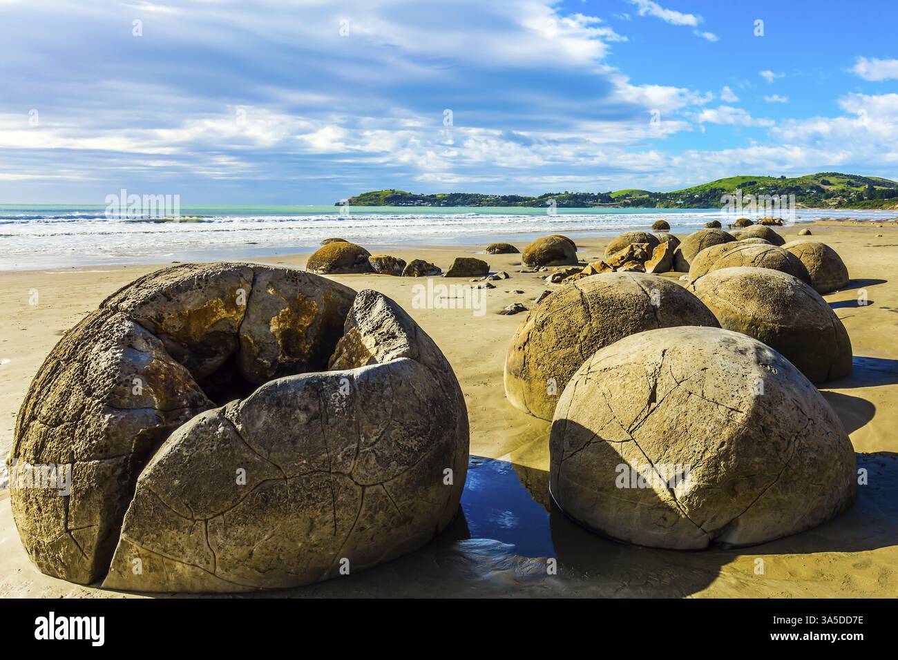 The large spherical boulders Moeraki and their remains on sandy beach ...