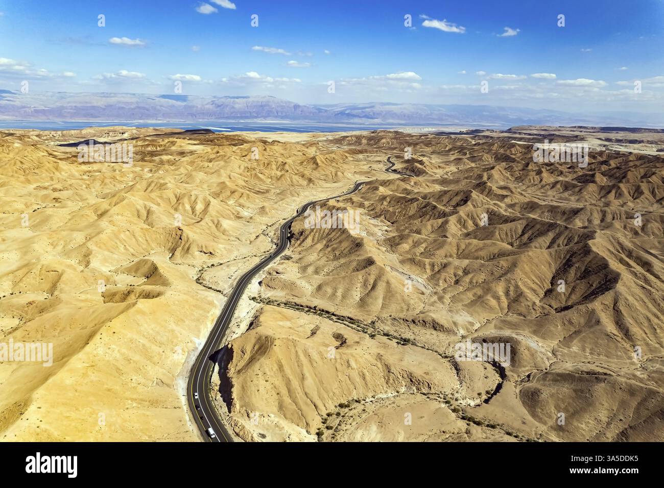 Desert on the shores of the Dead Sea. Asphalt highway meanders among ...
