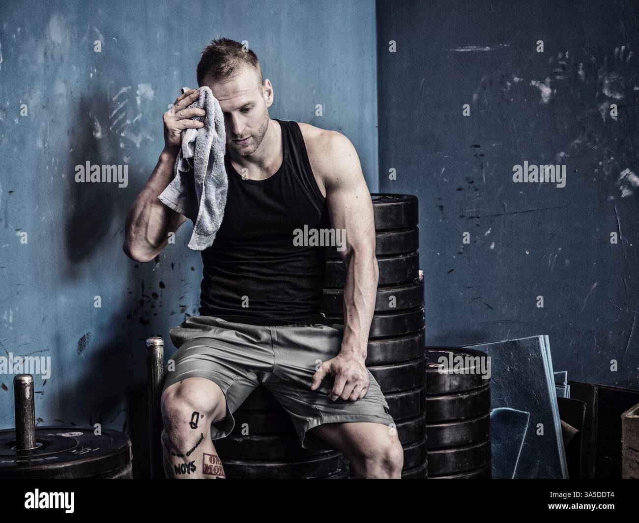 Muscular young bodybuilder drying sweat from his face with a towel ...