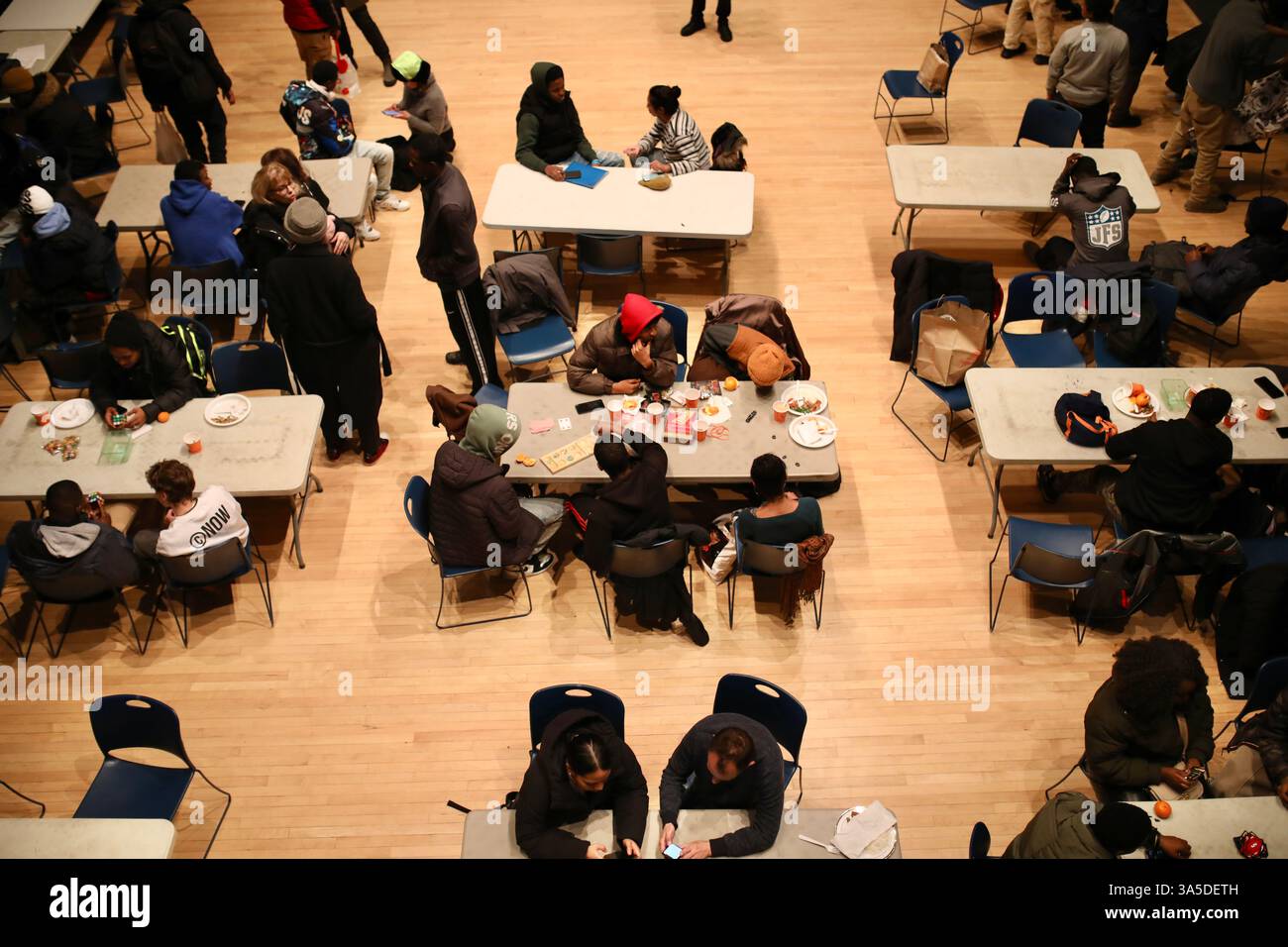New York, USA. 19th Feb, 2025. Migrants chat, relax, share a meal and ...