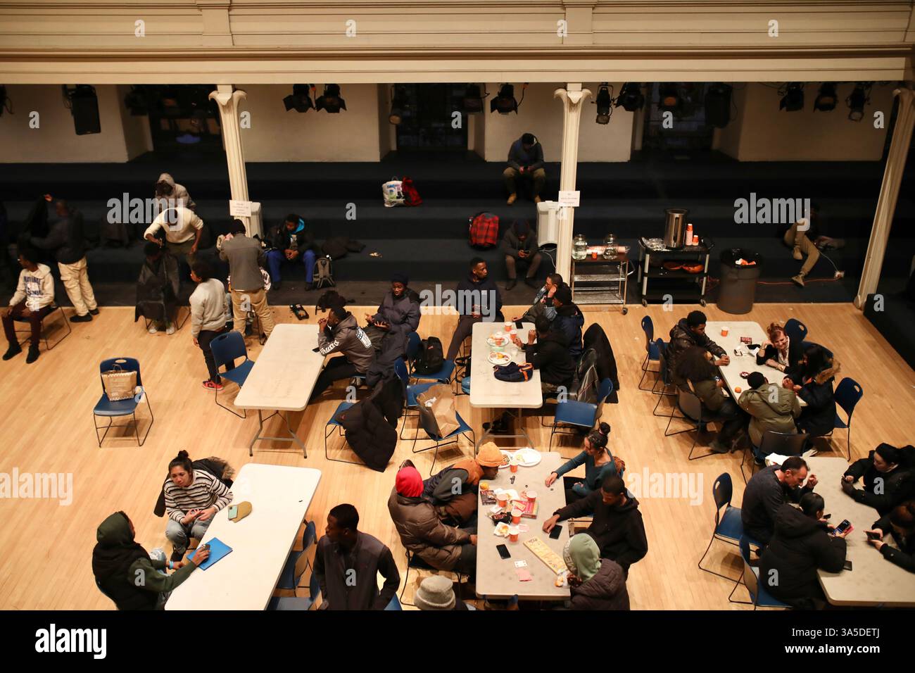 New York, USA. 19th Feb, 2025. Migrants chat, relax, share a meal and ...
