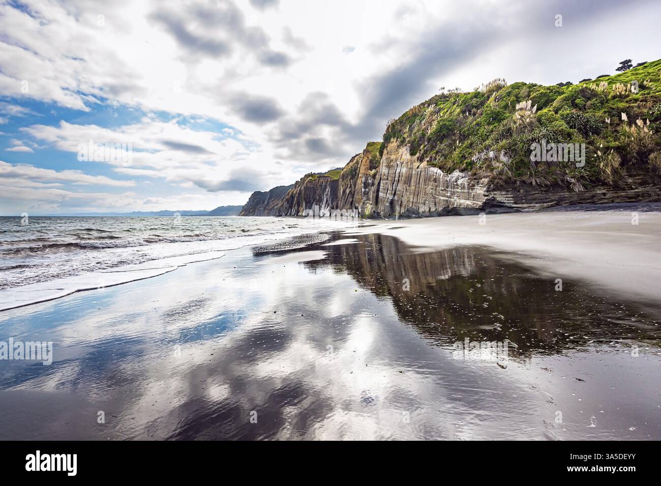 Thin layer of water on smooth sand reflects the sky. Low tide in the ...