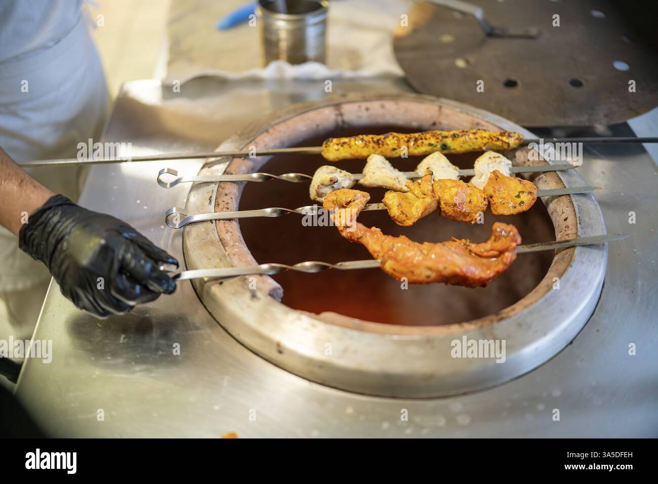 Chicken, fish, and paneer tikka are cooking in a traditional clay ...