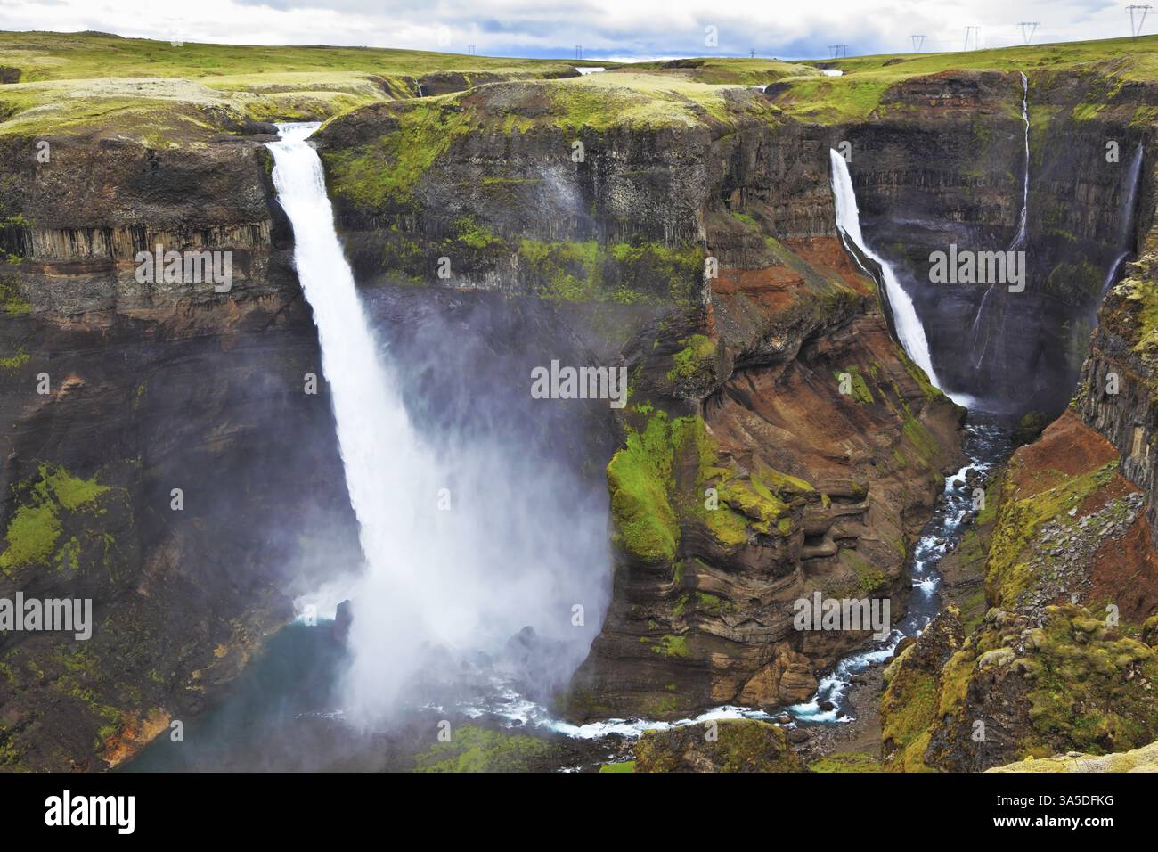 Vertical cliff, from which the powerful waterfall flies on black stones ...